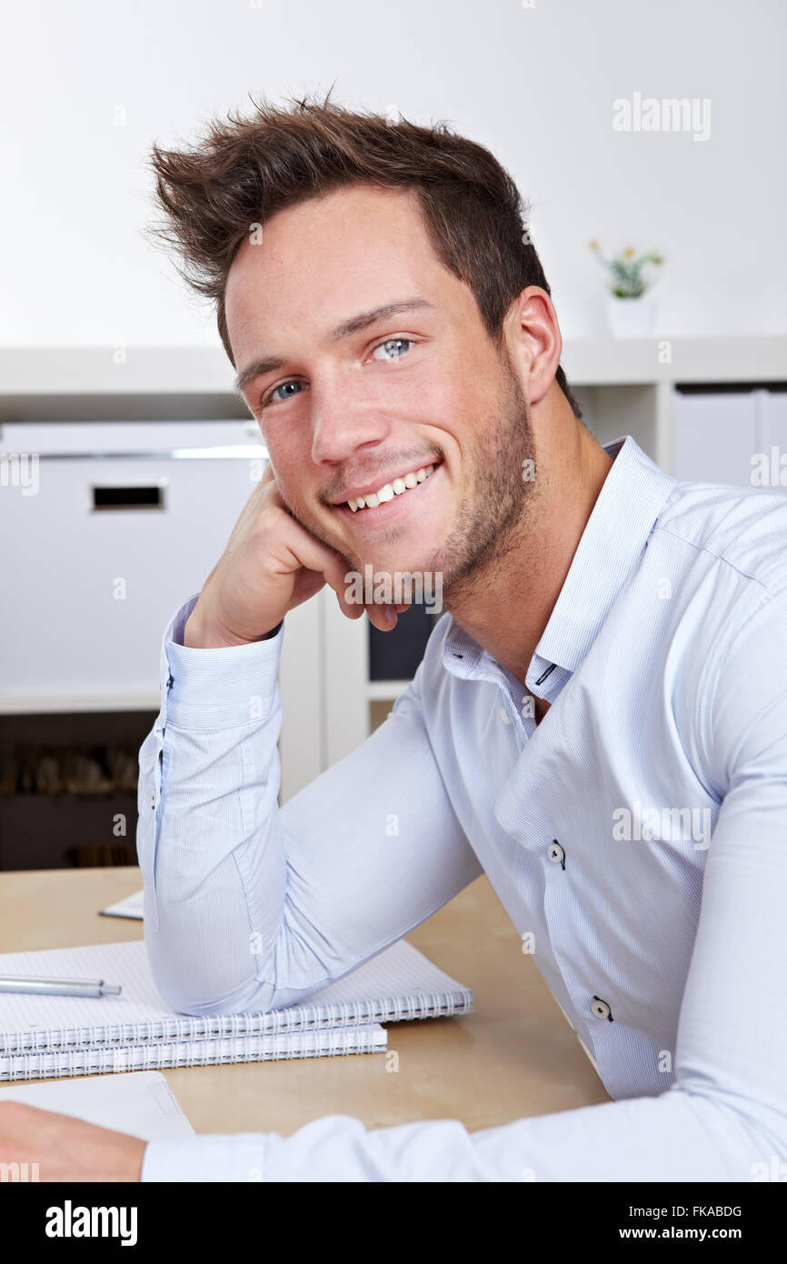 Portrait of happy smiling college student sitting at desk Stock Photo ...