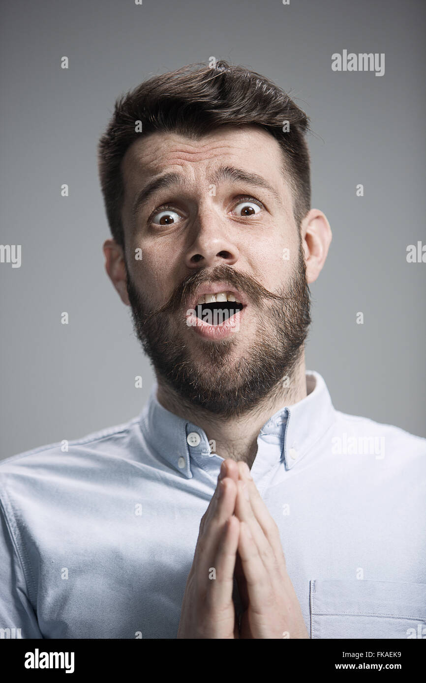 Man wearing a blue shirt is looking imploring. Over gray background ...