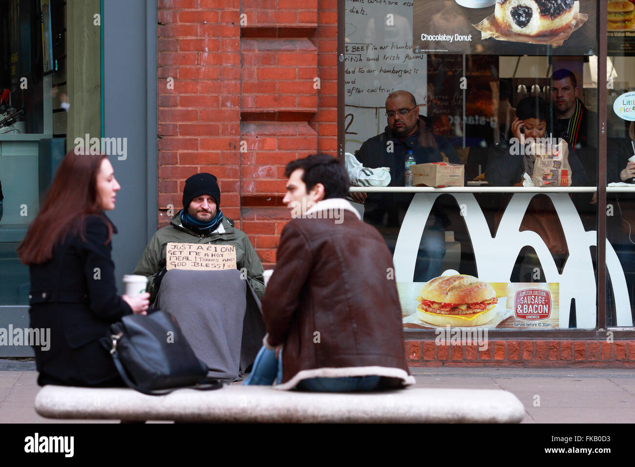 Two people sitting and drinking while a homeless man sits next to a ...