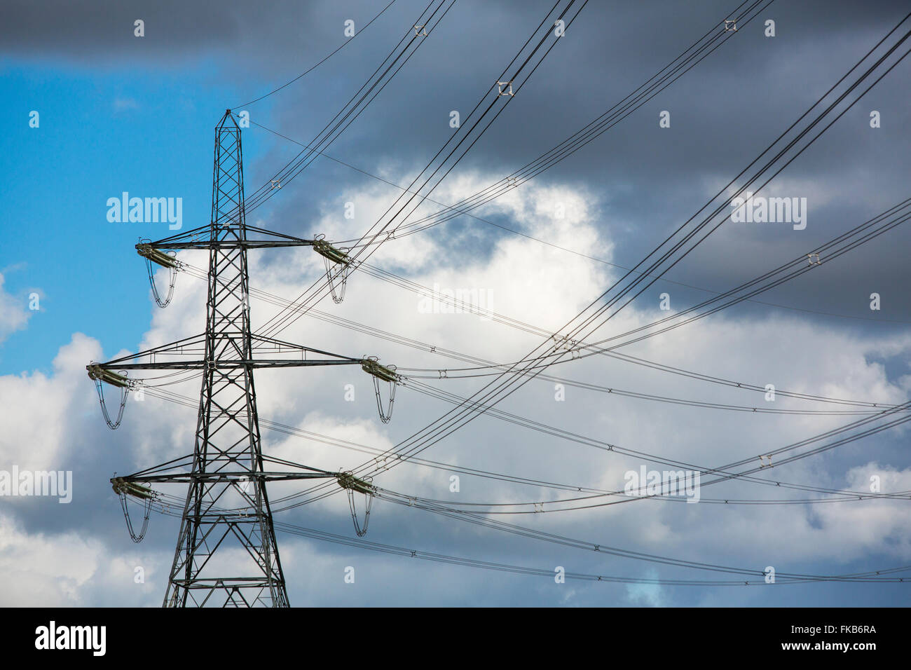 Electricty cables from pylons set against a blue and cloudy sky Stock ...