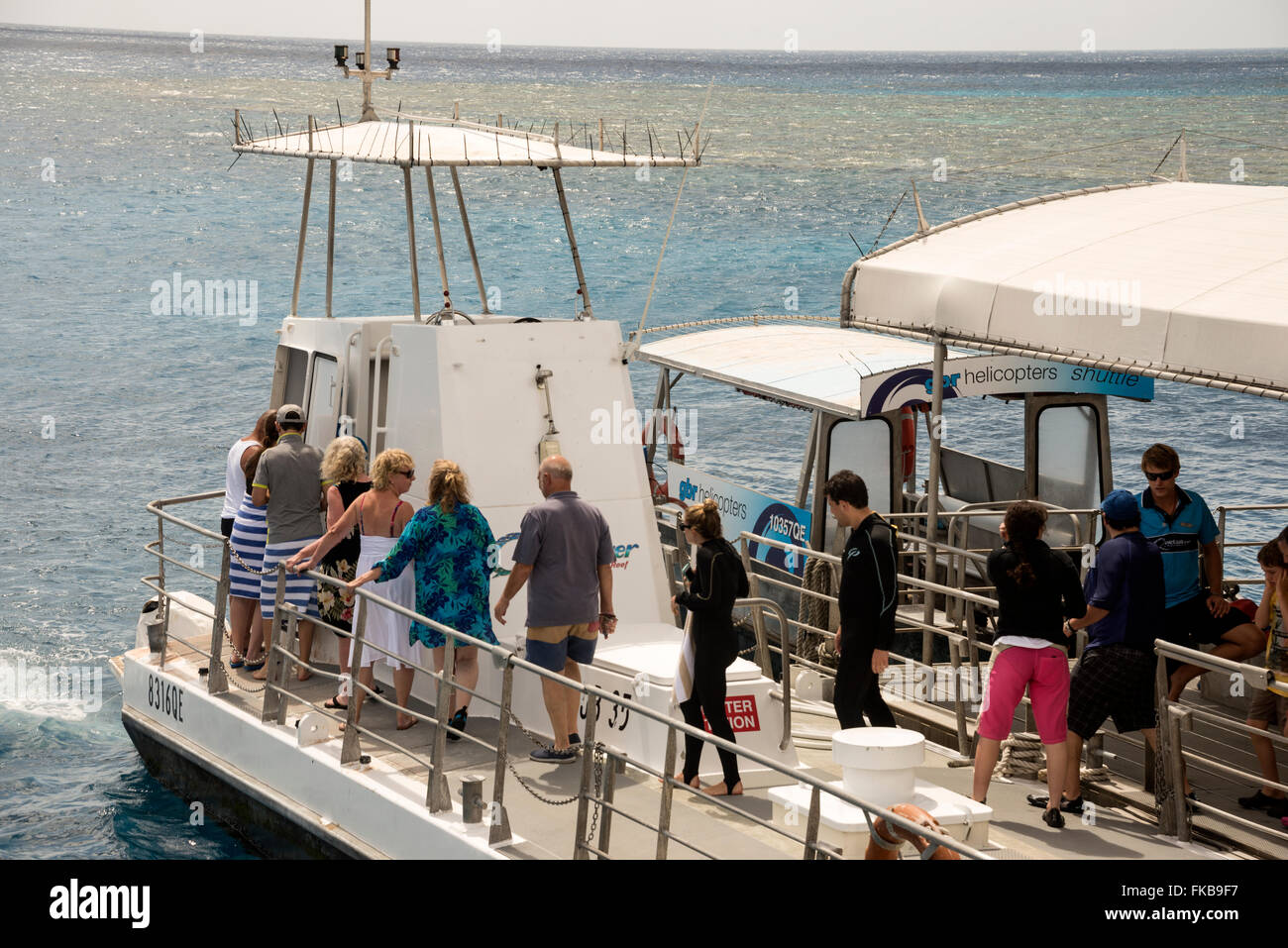 Small groups of tourists climb aboard a mini-submarine from the ...