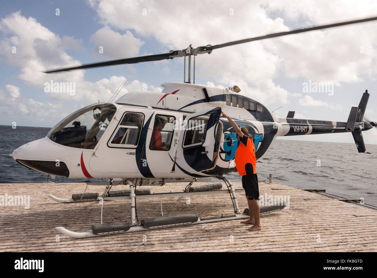 A helicopter lands on a small floating Heli-platform with a group of ...