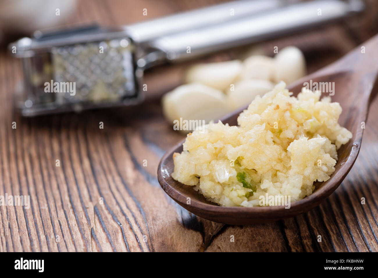 Fresh pressed Garlic (detailed close-up shot) on rustic wooden ...