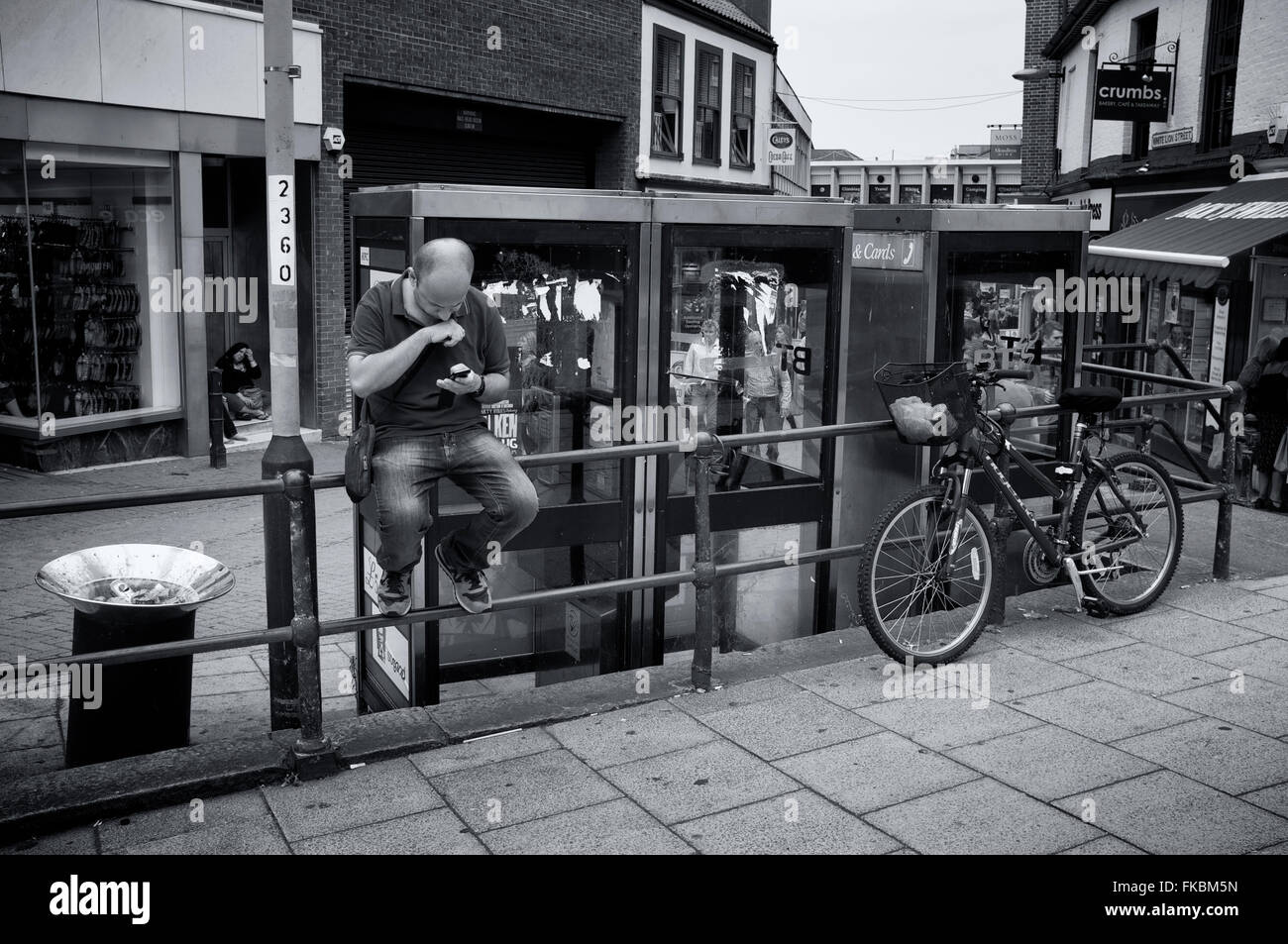 Man on his phone outside three phone boxes Stock Photo - Alamy