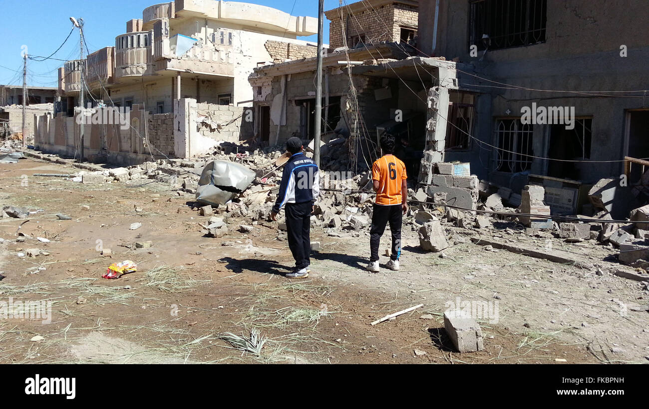 Fallujah, Iraq. 8th Mar, 2016. Two men stand in front of a destroyed ...