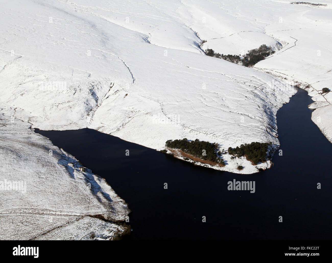 aerial view of a reservoir on The Pennines surrounded by snow capped ...