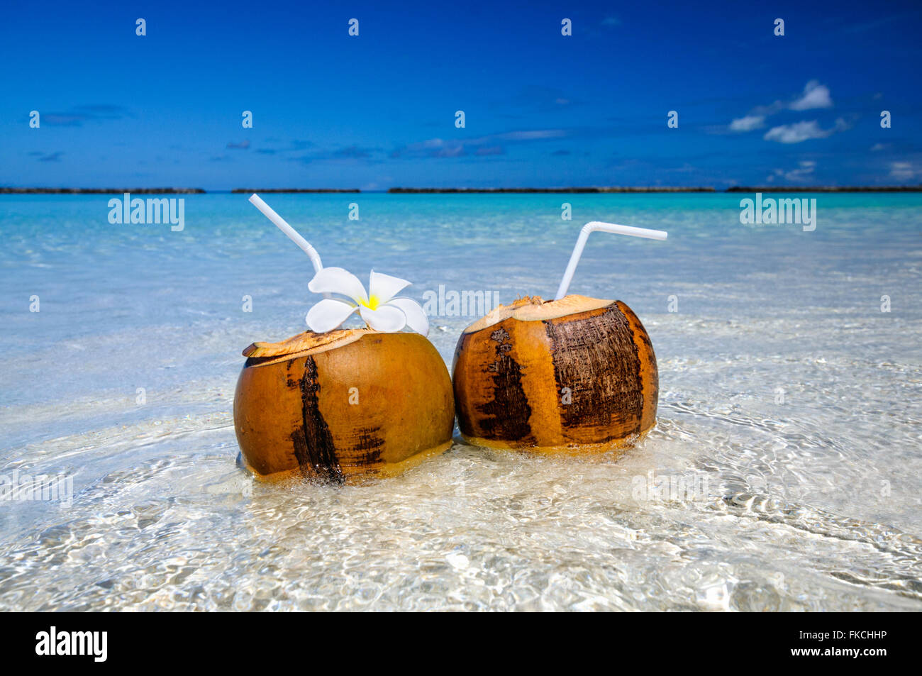 Two coconut cocktails on white sand beach next to clean sea water ...