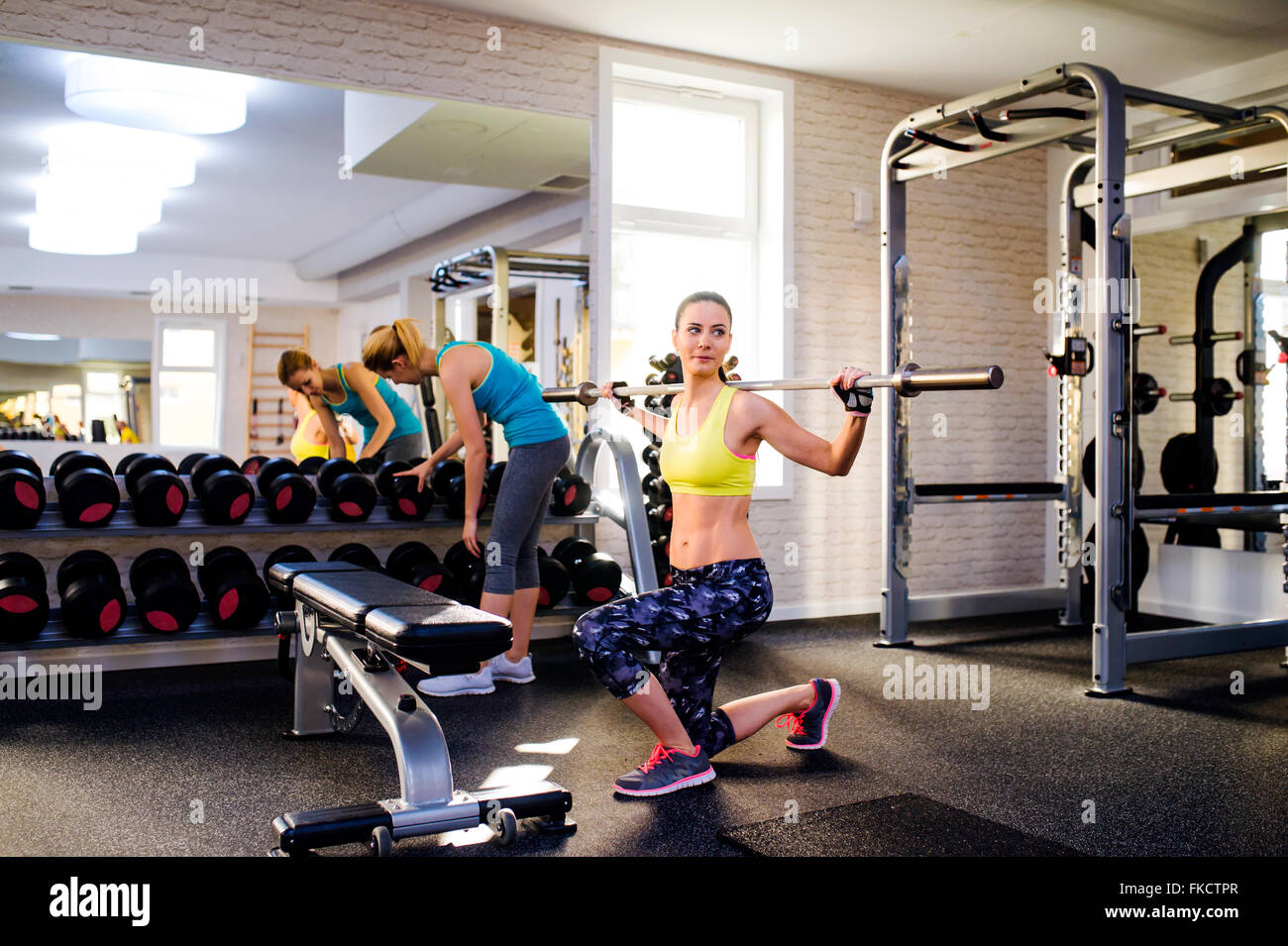 Women in gym exercising with weights and bar Stock Photo - Alamy