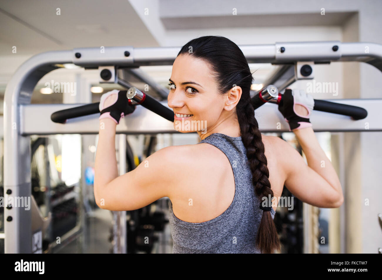 Woman in gym flexing back muscles on cable machine Stock Photo - Alamy