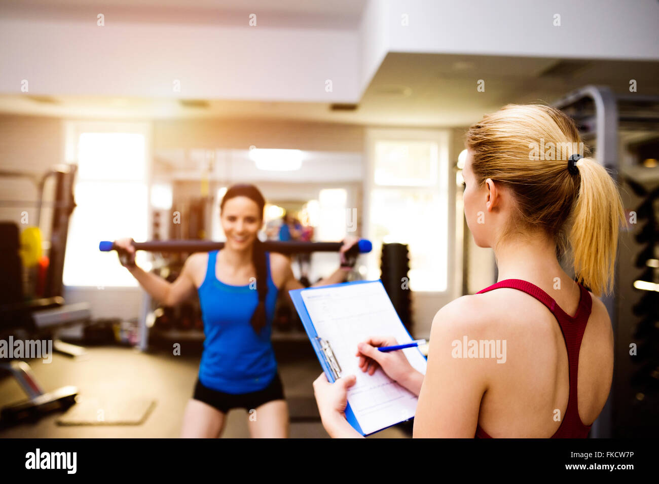 Woman exercising in gym, personal trainer, plan on clipboard Stock ...