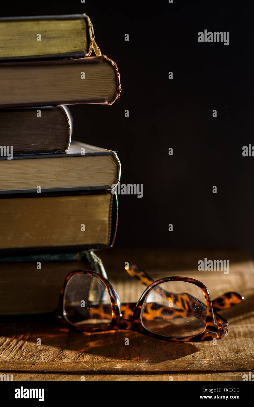 Eyeglasses and stack of books on table Stock Photo - Alamy