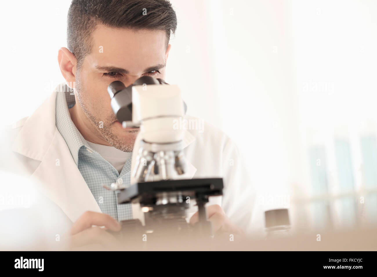 Man looking through microscope Stock Photo - Alamy