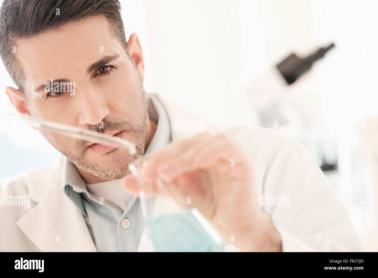 Man pouring liquid into conical flask Stock Photo - Alamy