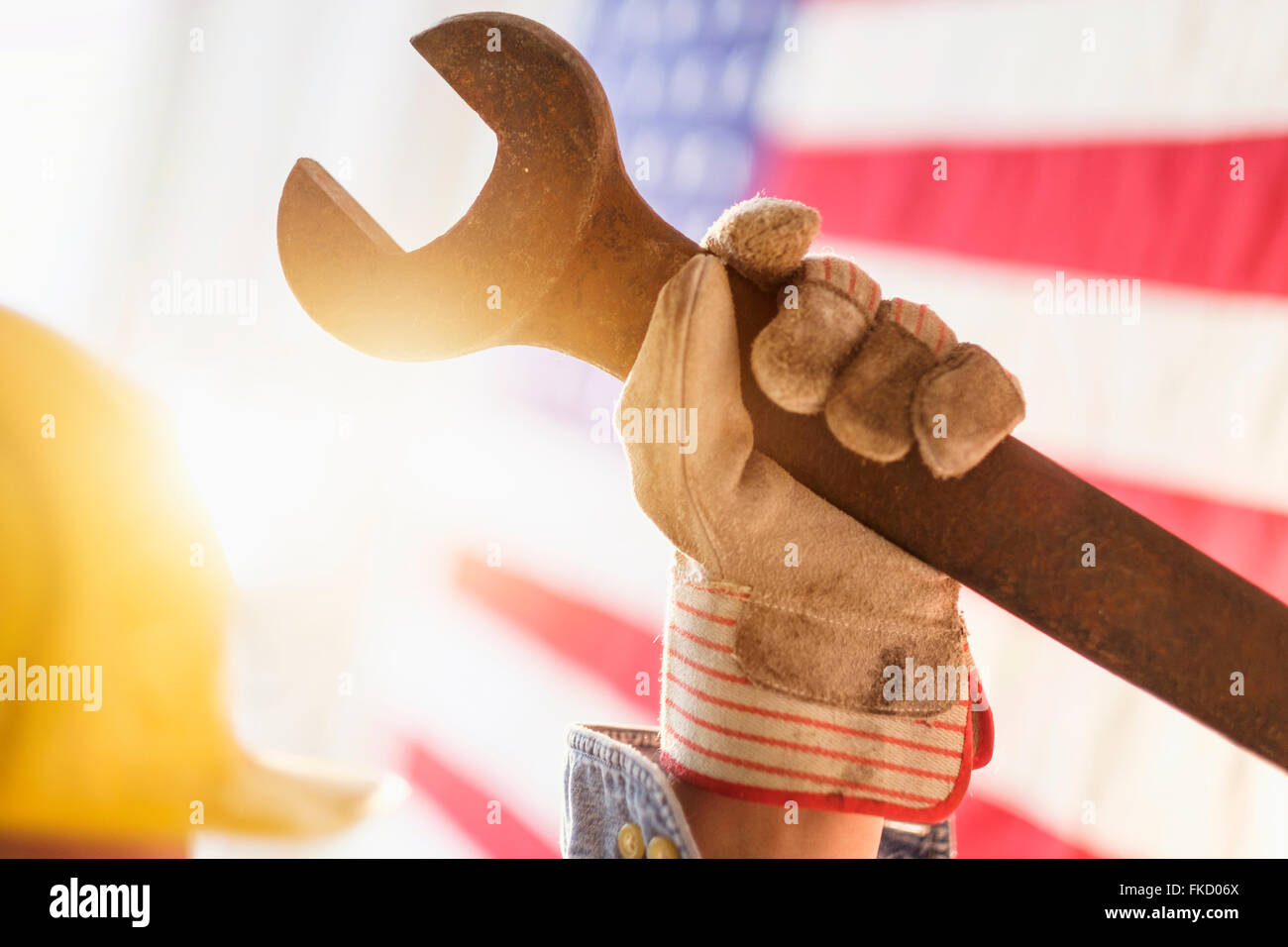 Manual worker's hand holding wrench with American flag in background ...
