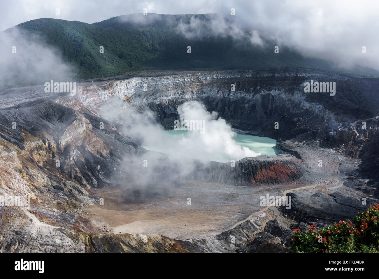 Steam erupting from active volcano with mountain range in background ...