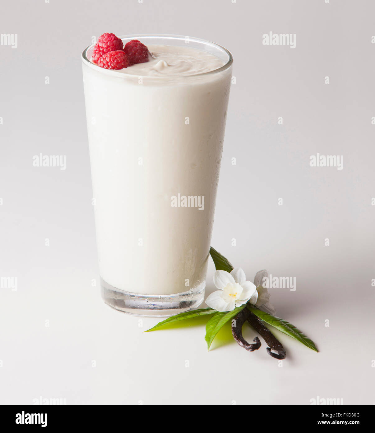 Vanilla smoothie in glass decorated with raspberry Stock Photo - Alamy