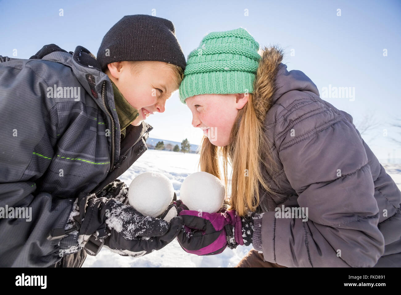 Children (8-9, 10-11) holding snowballs and touching foreheads Stock ...