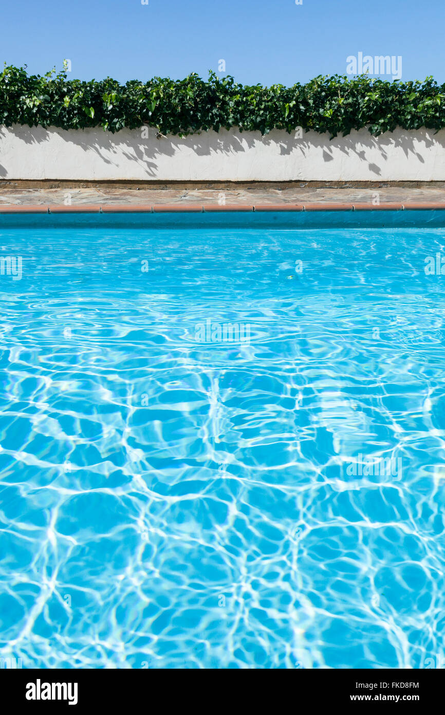 ripples in empty swimming pool with ivy on wall and blue sky Stock ...