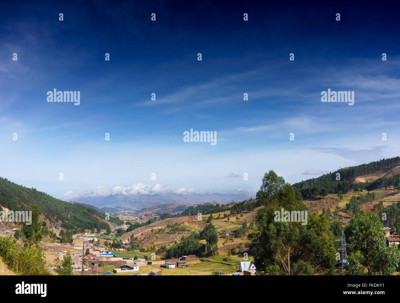 Village on hill with mountain in background against blue sky, Cusco ...