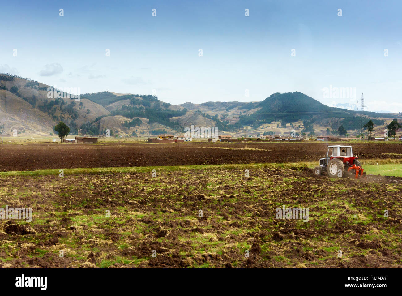 Tractor ploughing field with mountain range in background, Cusco, Peru ...