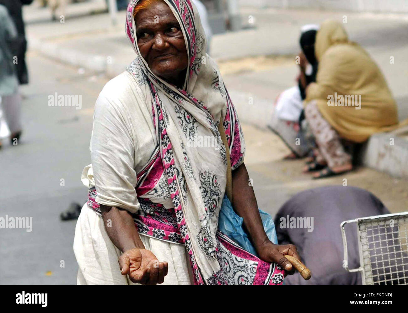 Poor aged woman beggar begs for alms at a roadside near mosque on the ...