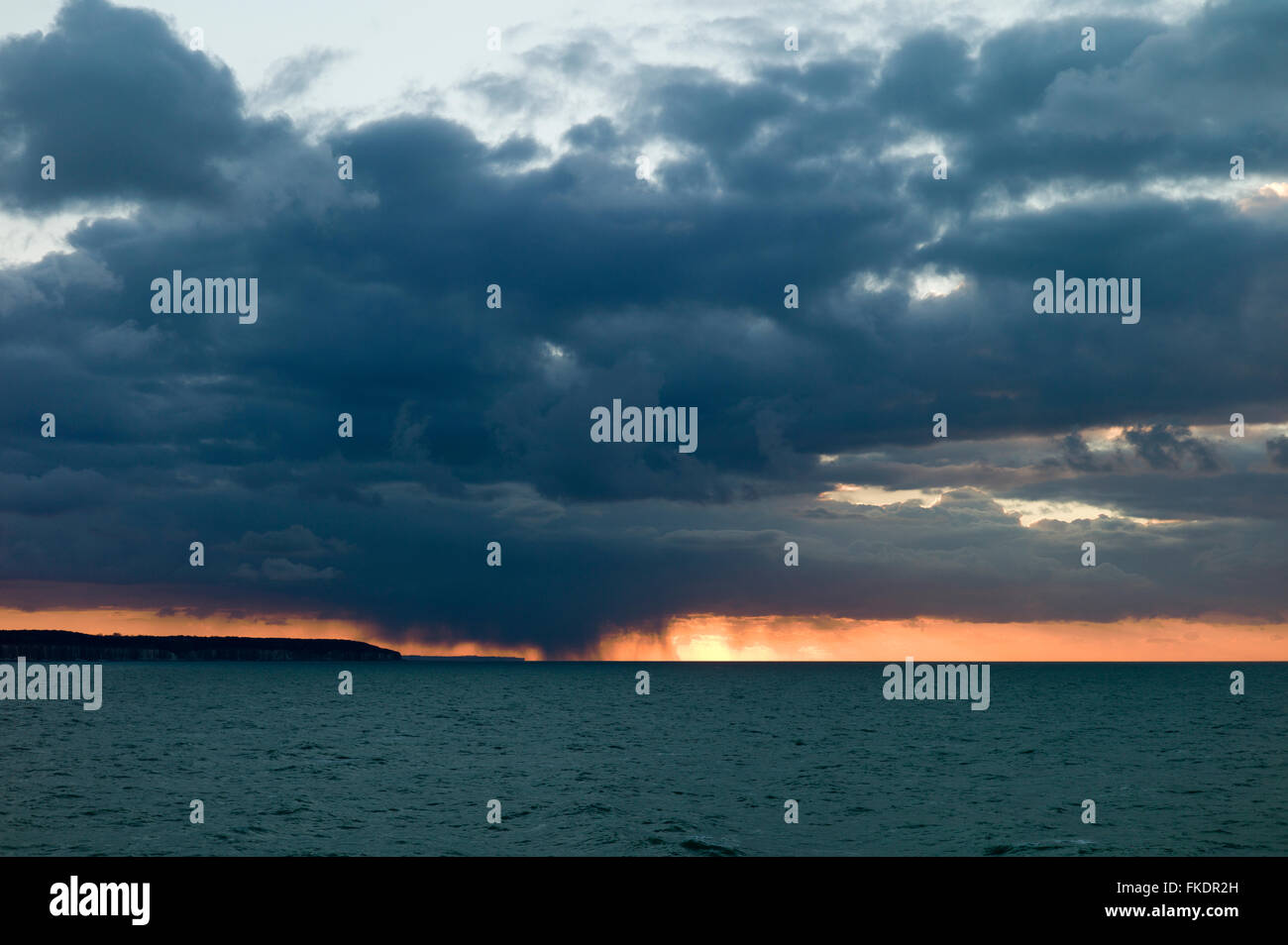 Sunset over sea with falling rain and rainclouds, Normandy, France ...