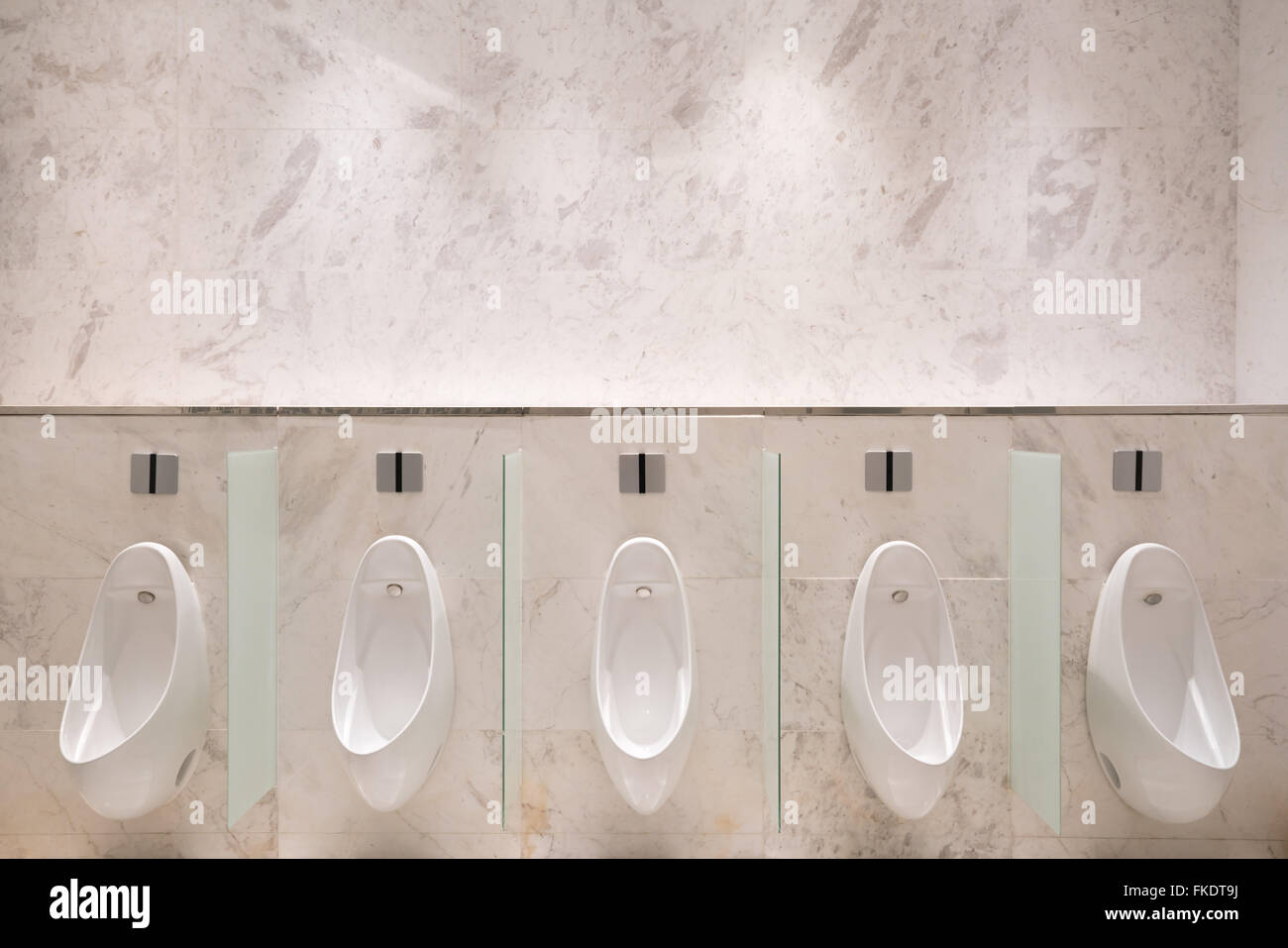 Row of five urinals with infrared sensor, on marble wall, in men's ...