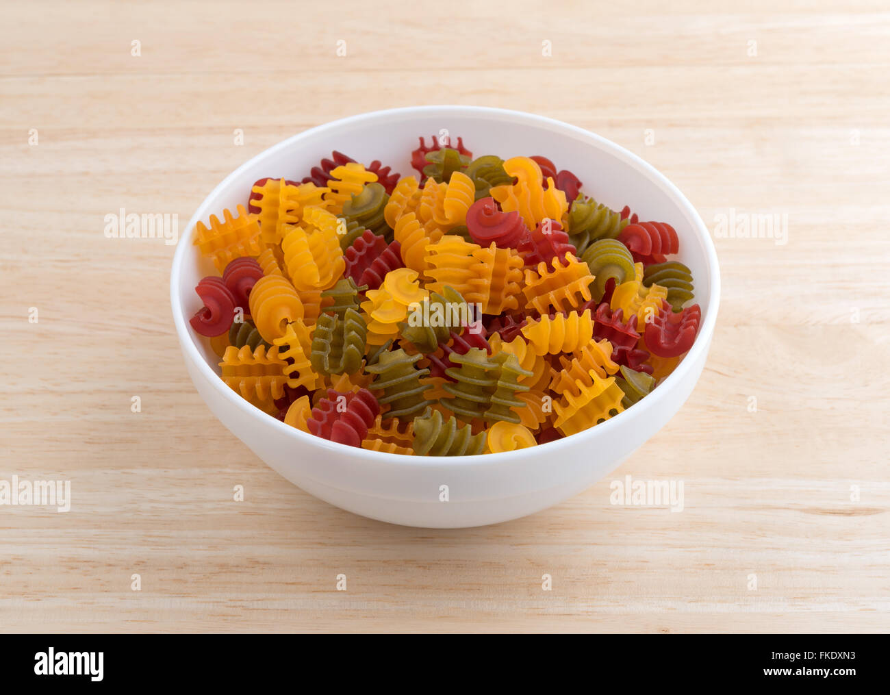 A portion of gluten free corn vegetable radiatore pasta in a white bowl ...