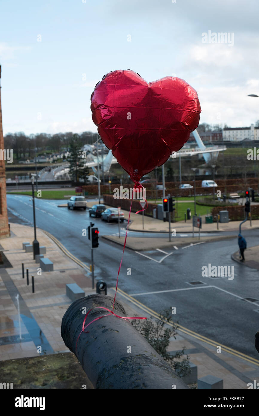 Red balloon tied to a cannon on Derry City Walls with the Peace Bridge ...