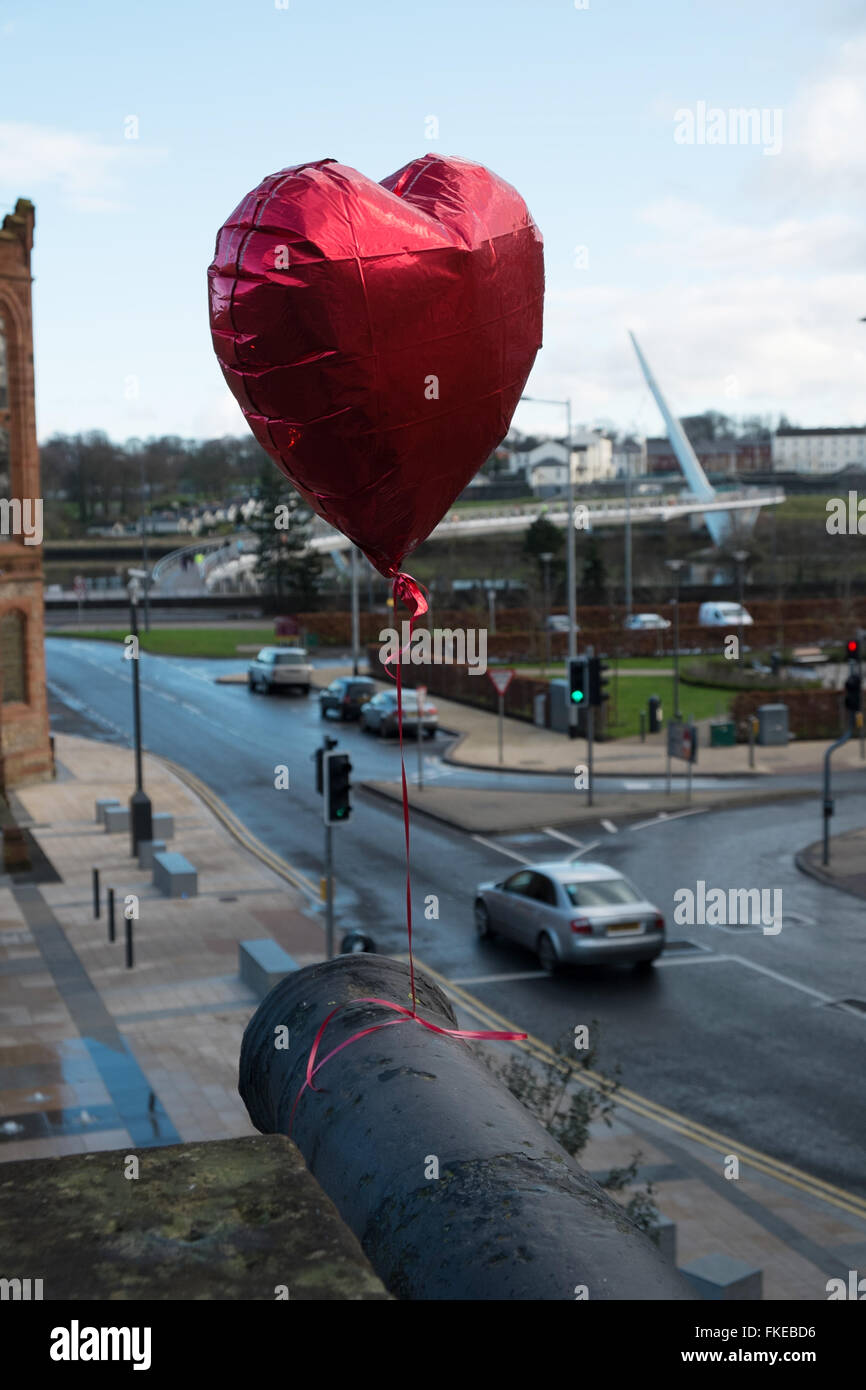 Red balloon tied to a cannon on Derry City Walls with the Peace Bridge ...