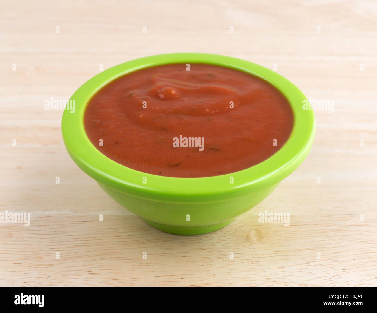 Side view of a bowl of pizza sauce on a wood table top Stock Photo - Alamy