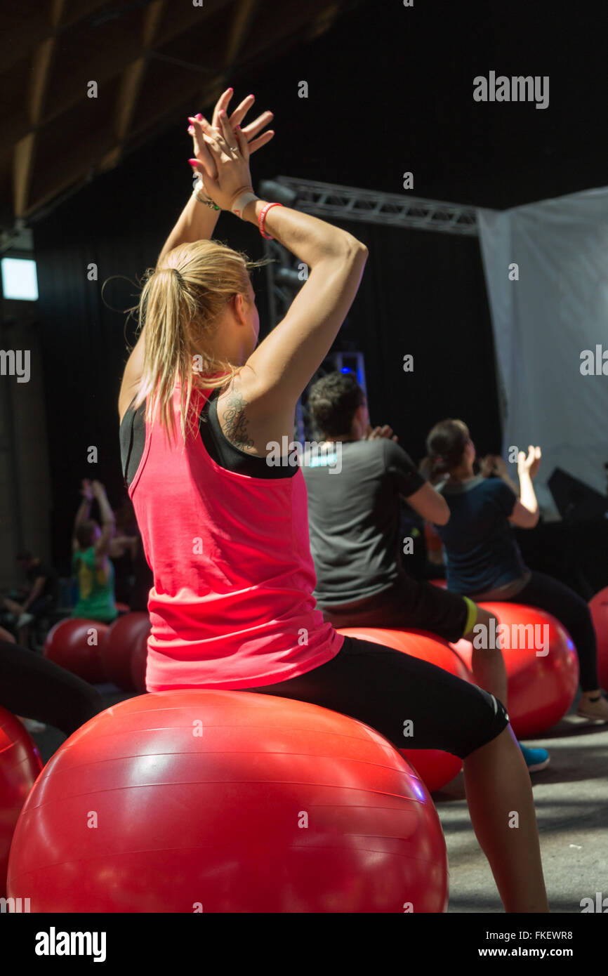 Blonde Young Girl doing Fitness Activity Sitting on Big Red Ball in Gym ...