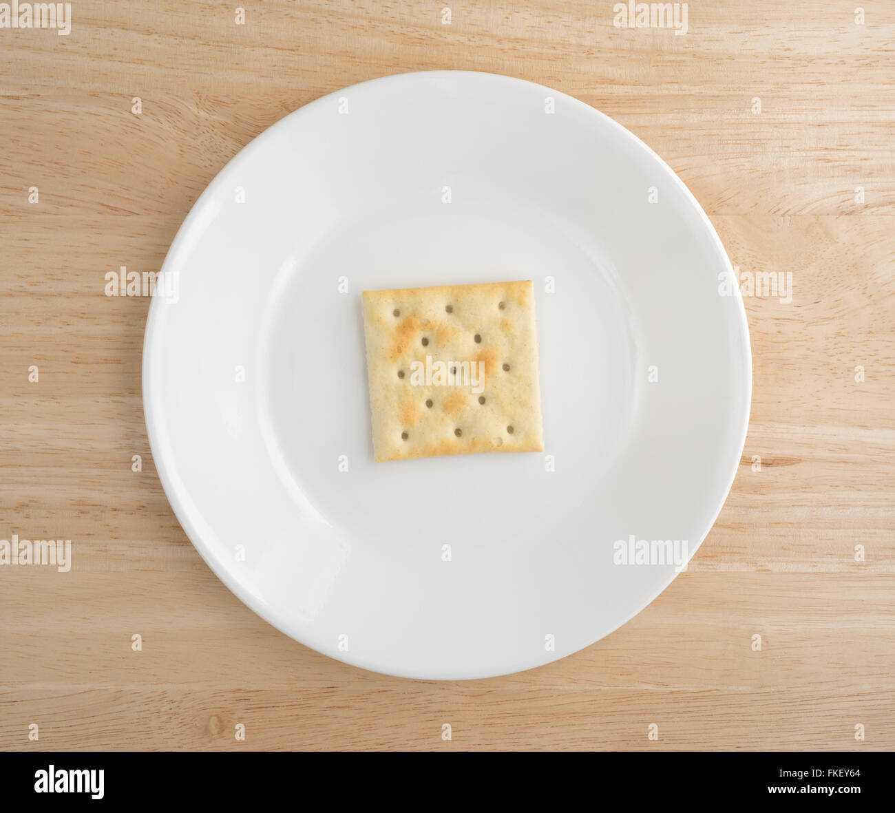 Top view of an unsalted saltine cracker on an off white plate atop a ...