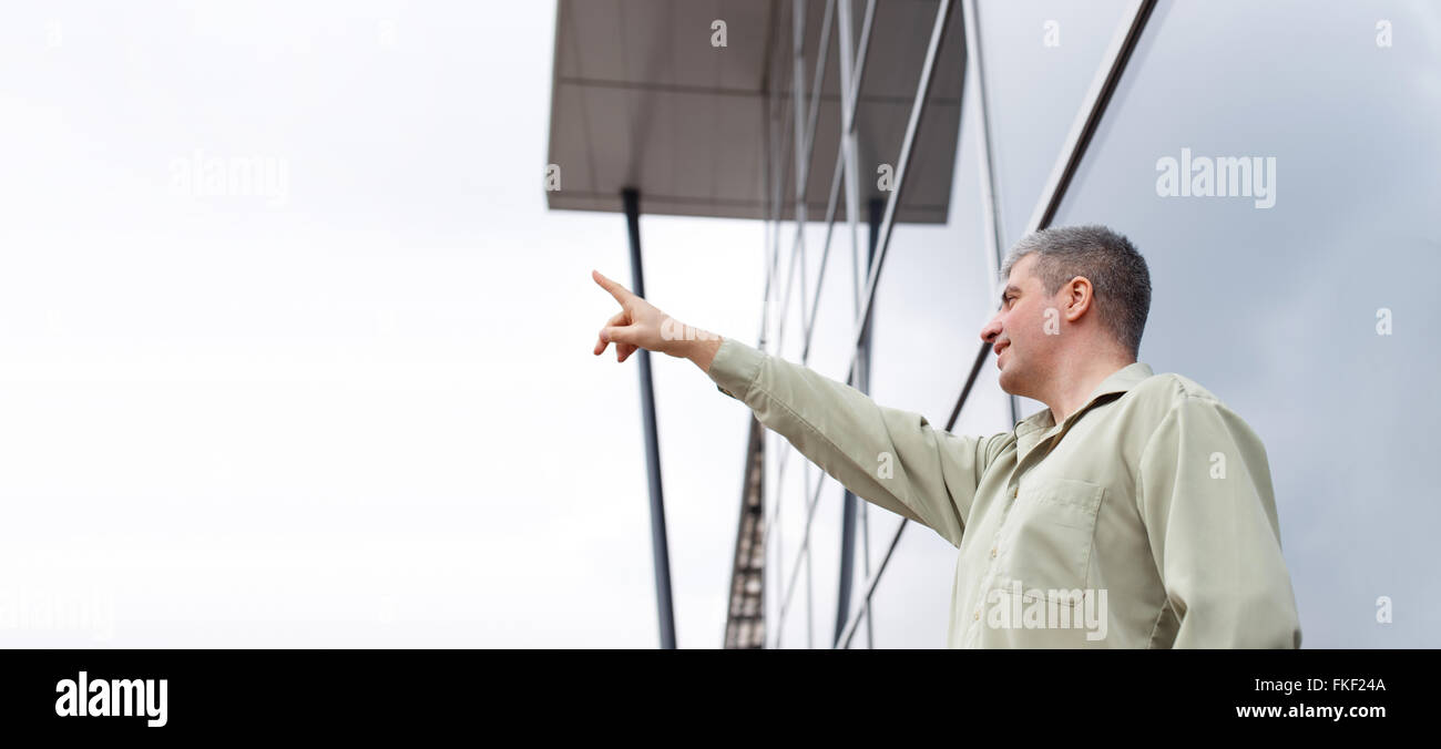 Young businessman pointing to sky at business center Stock Photo - Alamy
