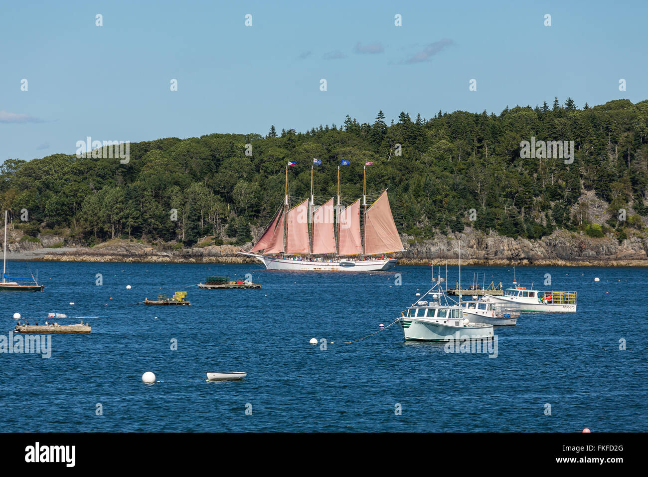 A four masted schooner touring sightseers through a blue harbor off Bar ...