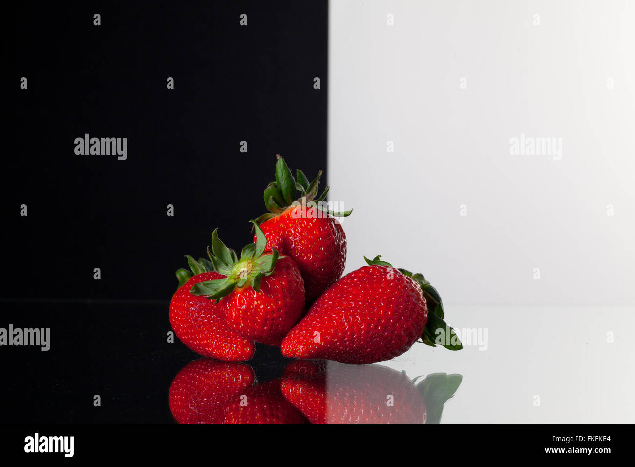 Fresh strawberries isolated on black and white background and glass ...