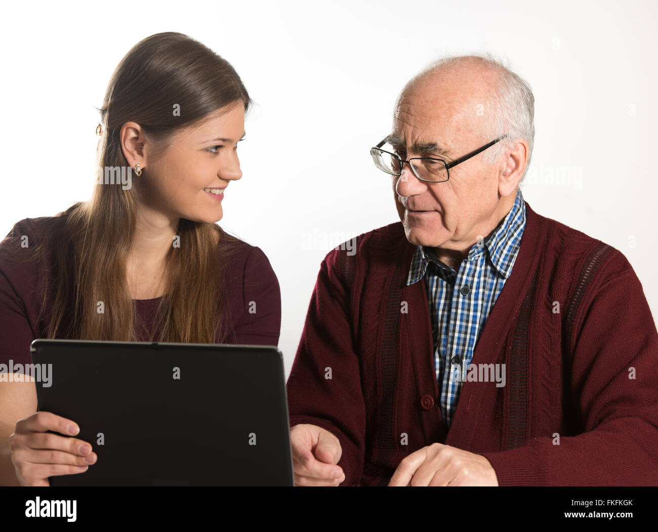 young woman helping senior man to work with tablet computer and fill ...
