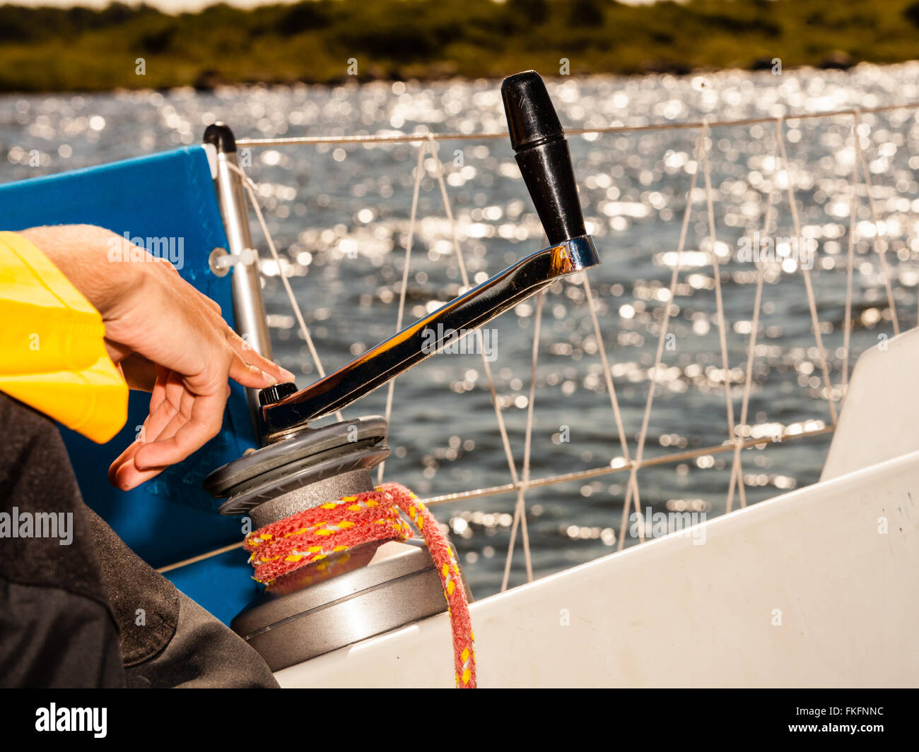 Male hand on winch capstan with rope on sailing boat. Yachting yacht in ...