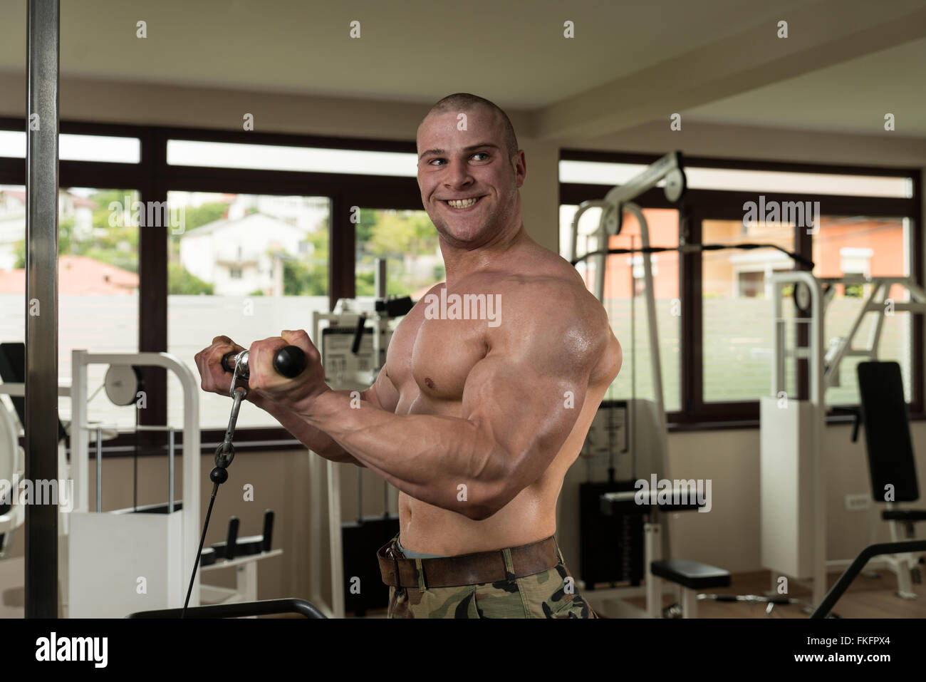 Muscular Man Doing Heavy Weight Exercise For Biceps On Machine In Gym ...