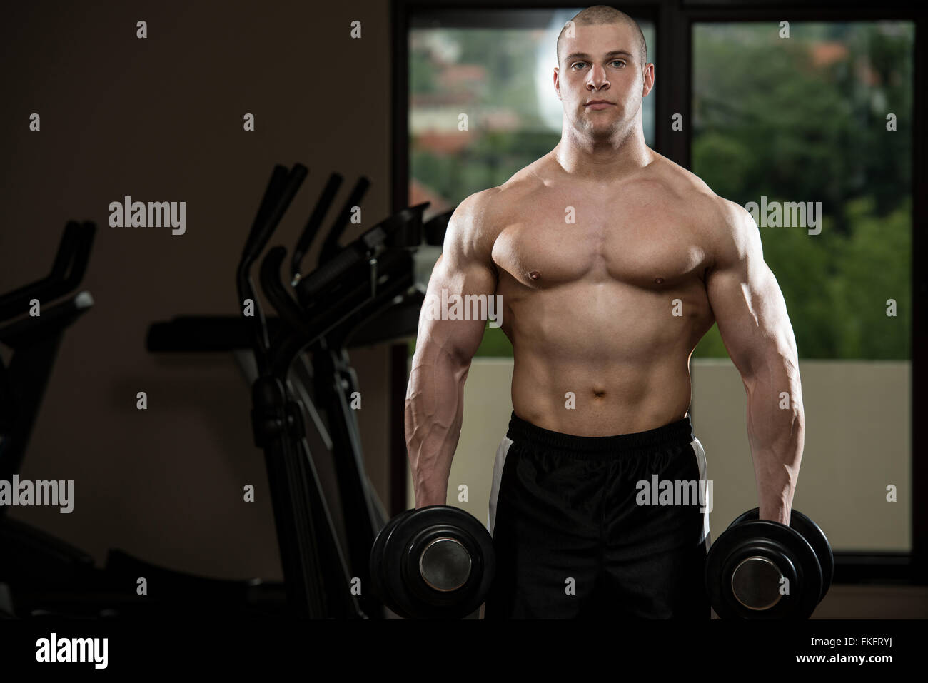 Bodybuilder Doing Heavy Weight Exercise For Biceps With Dumbbells In ...