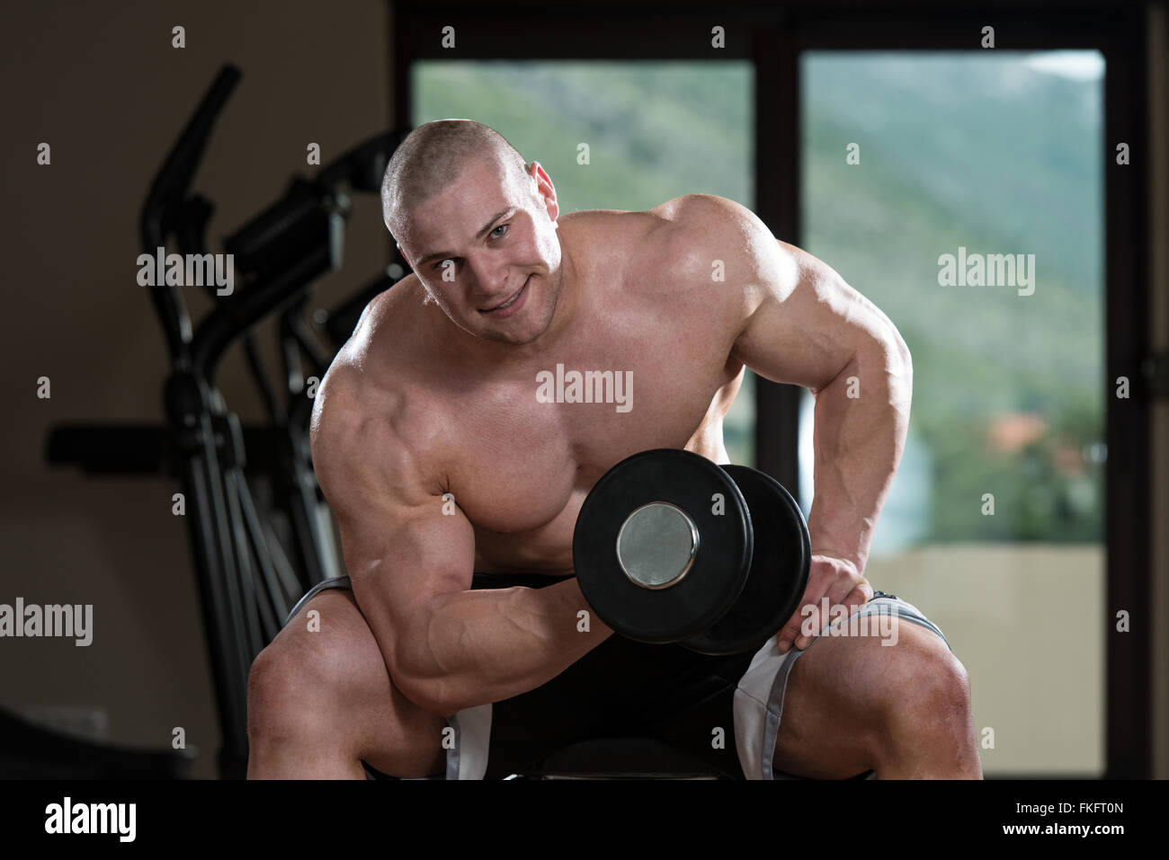 Muscular Man Doing Heavy Weight Exercise For Biceps With Dumbbells In ...
