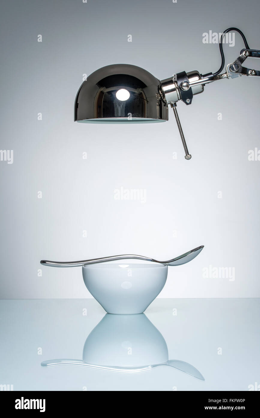 lighting up white ceramic bowl silver spoon with desk lamp on round ...