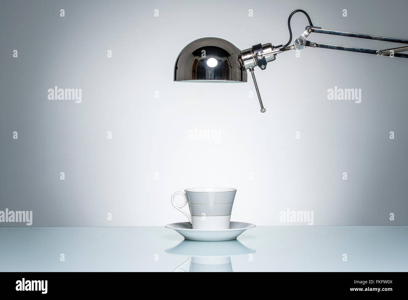 lighting up white mug coffee cup with desk lamp on round studio ...
