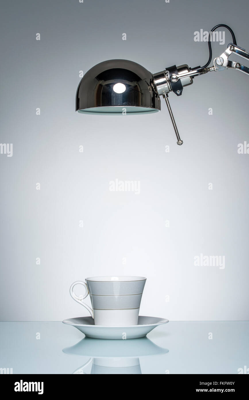 lighting up white mug coffee cup with desk lamp on round studio ...
