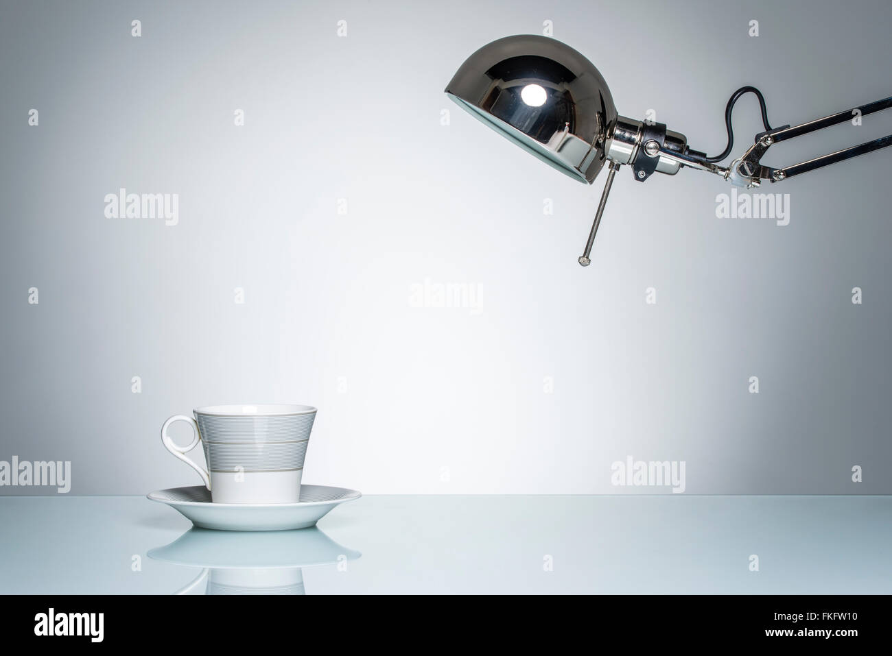 lighting up white mug coffee cup with desk lamp on round studio ...