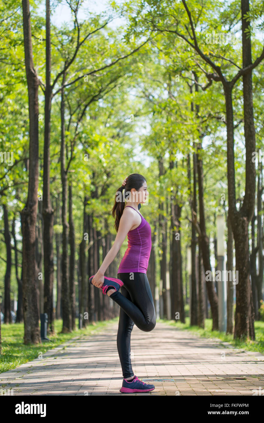 Sporty young asian woman stretching after jogging in the forest ...