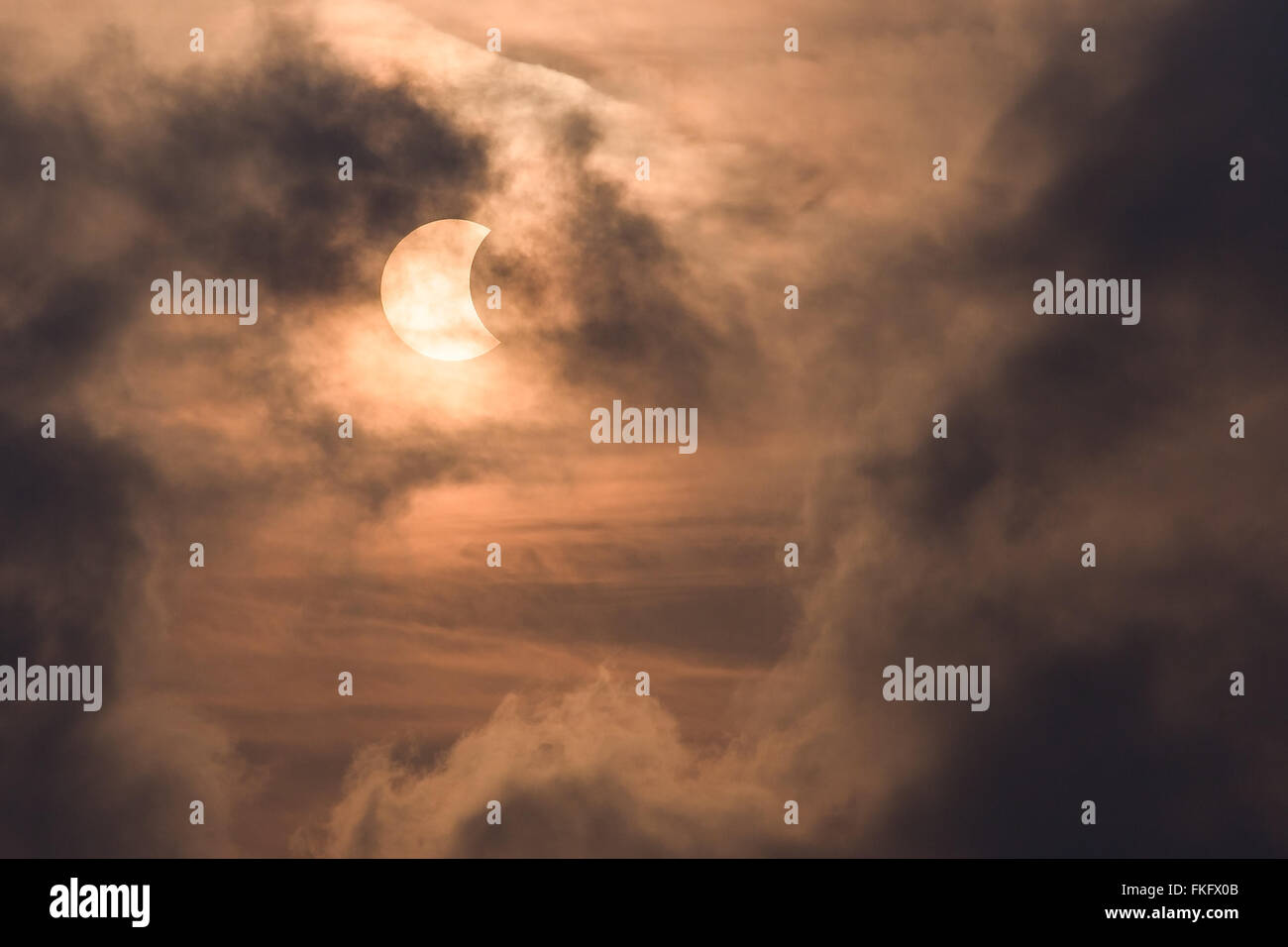 Partial sun eclipse (around 41 percent) behind dark cloude in Bangkok ...