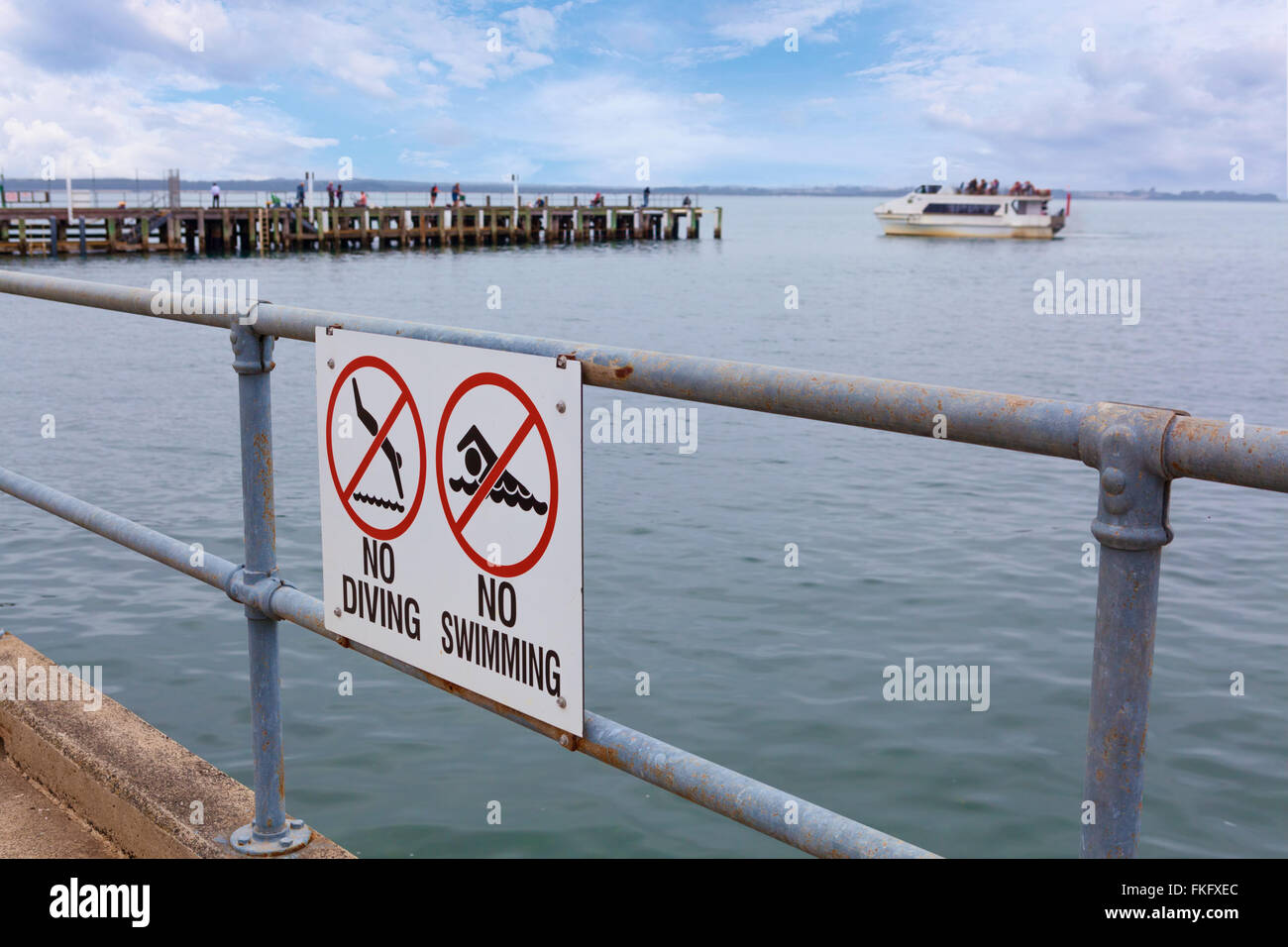 No Diving and No Swimming signs on pier railing with ocean water in the ...