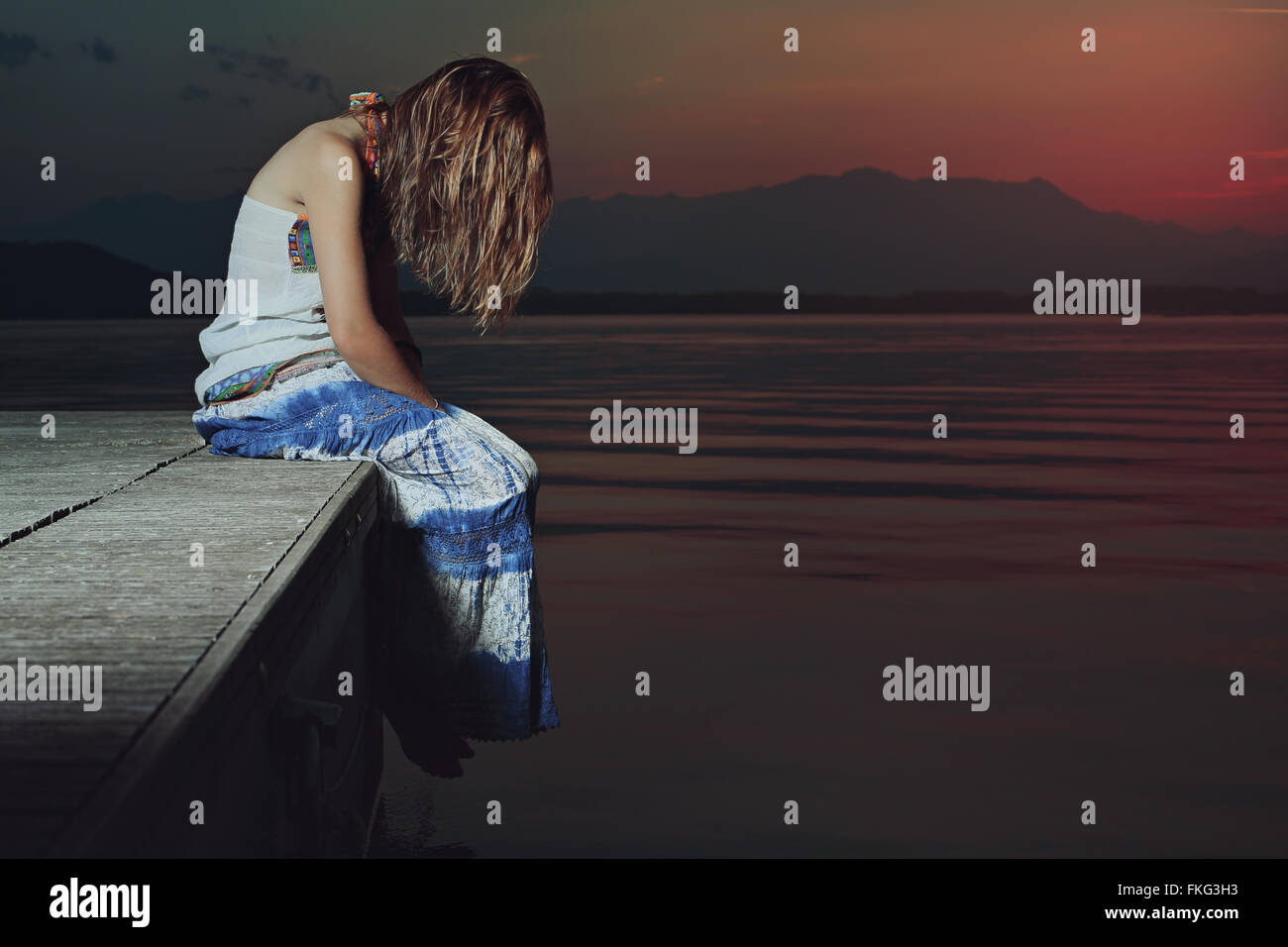 Lone woman in sad position over lake waters . Red dusk light Stock ...