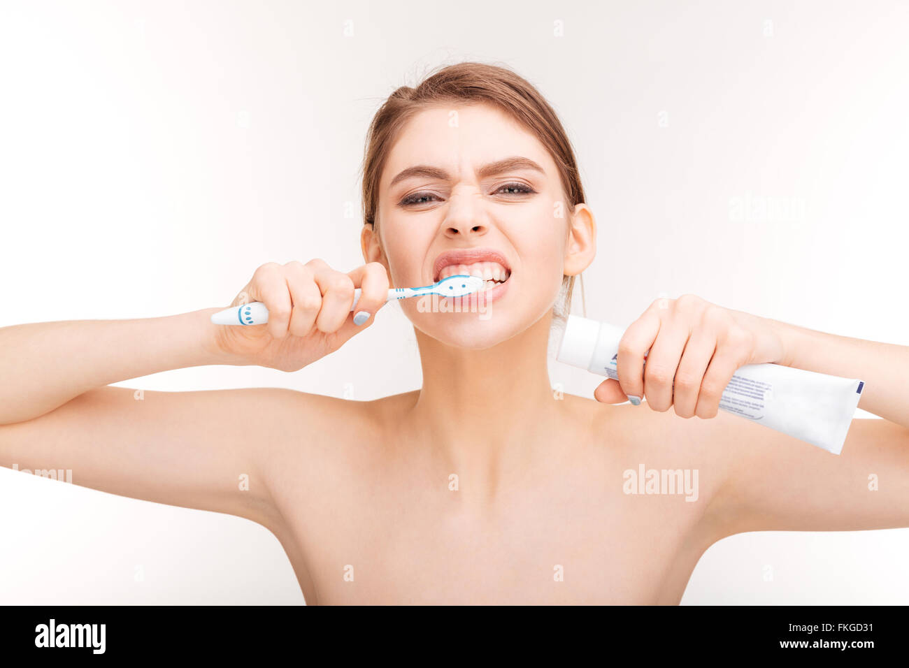 Portrait of beautiful young woman holding toothpaste and brushing her ...